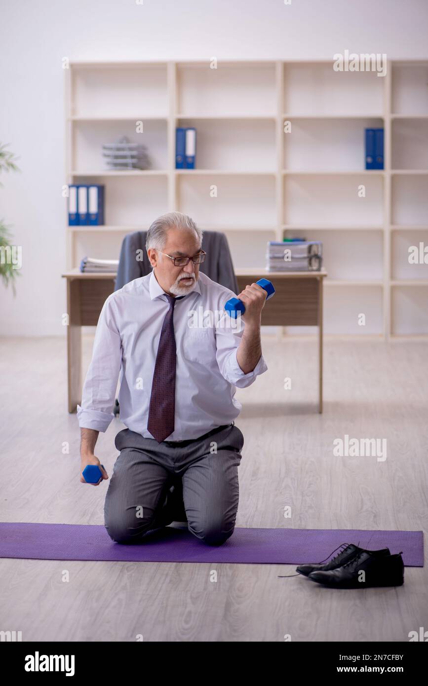 Old employee doing sport exercises during break Stock Photo - Alamy