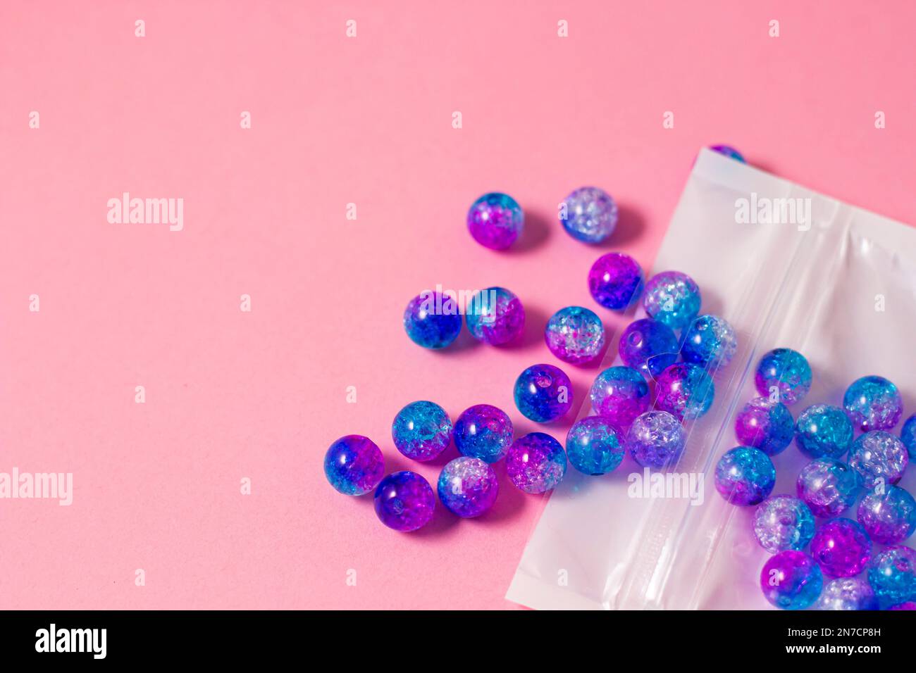 Glass colorful scattered beads on a pink background Stock Photo - Alamy