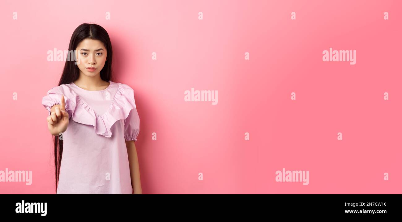 She says no. Serious asian girl shaking finger in stop gesture ...