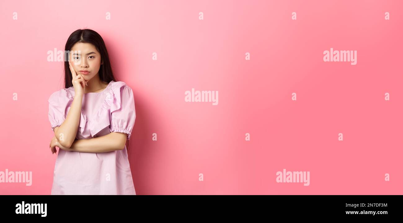 Bored asian teen girl look indifferent at camera, lean face on hand in ...