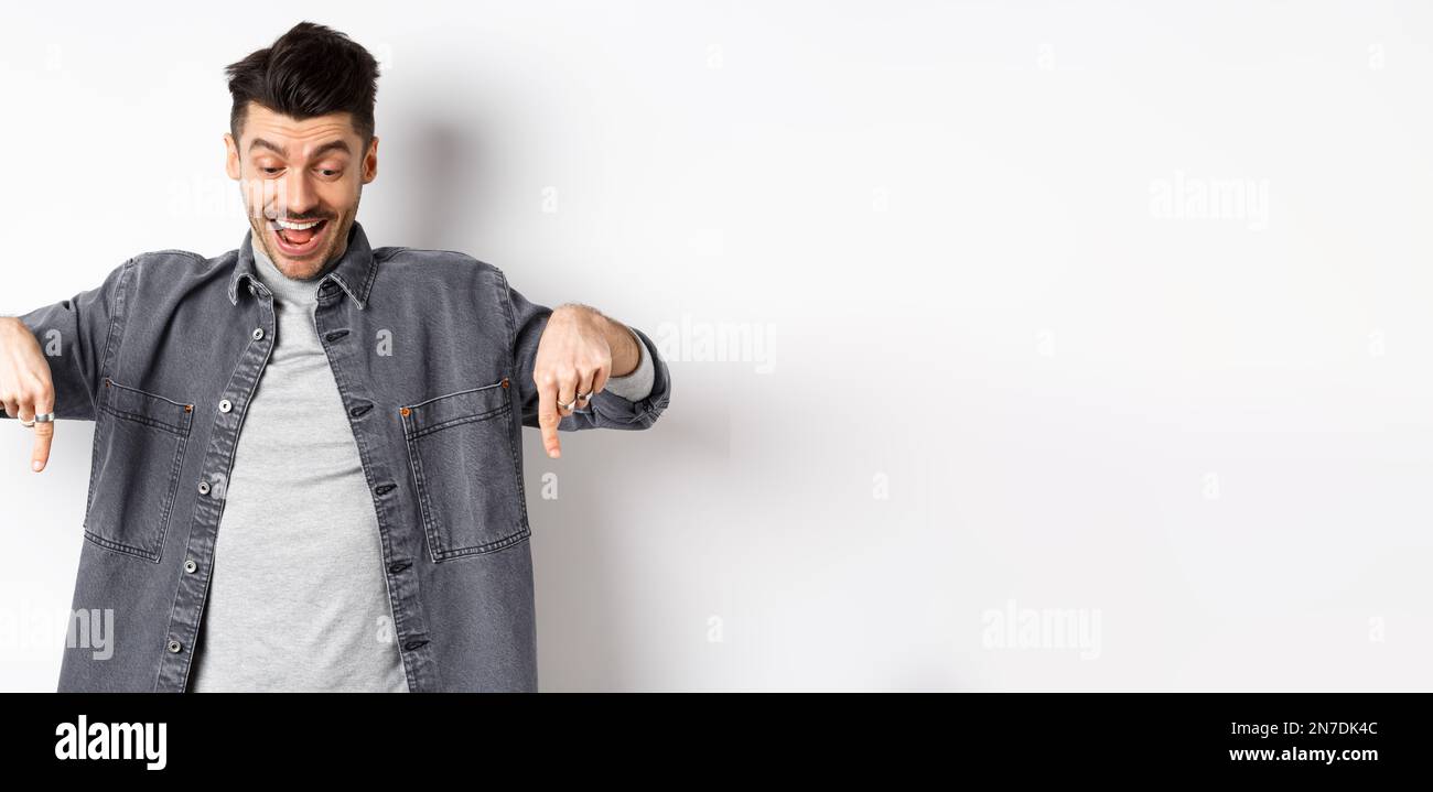 Excited european man looking and pointing fingers down, looking happy ...