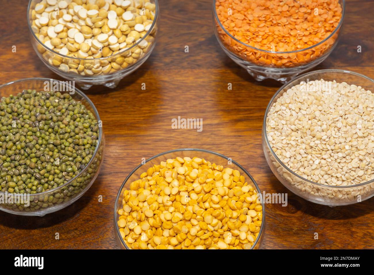 Bowls full of varieties of pulses spread over a wooden table with copy ...