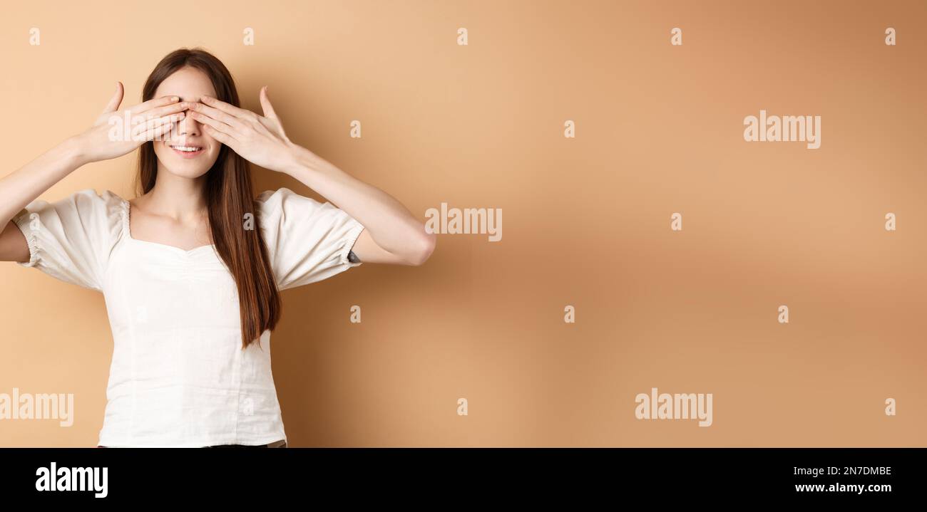 Happy romantic girl covering eyes and waiting for surprise, smiling ...