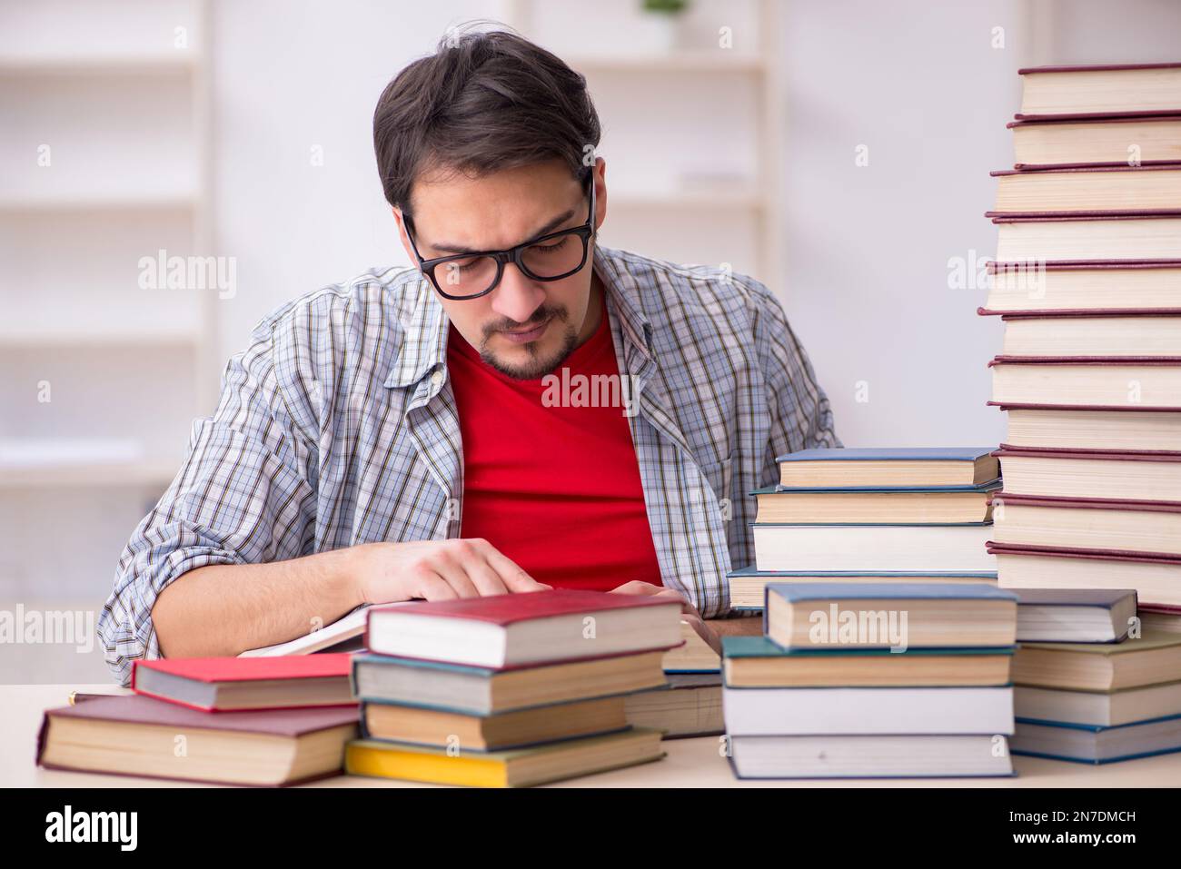 Young student and too many books in the classroom Stock Photo - Alamy