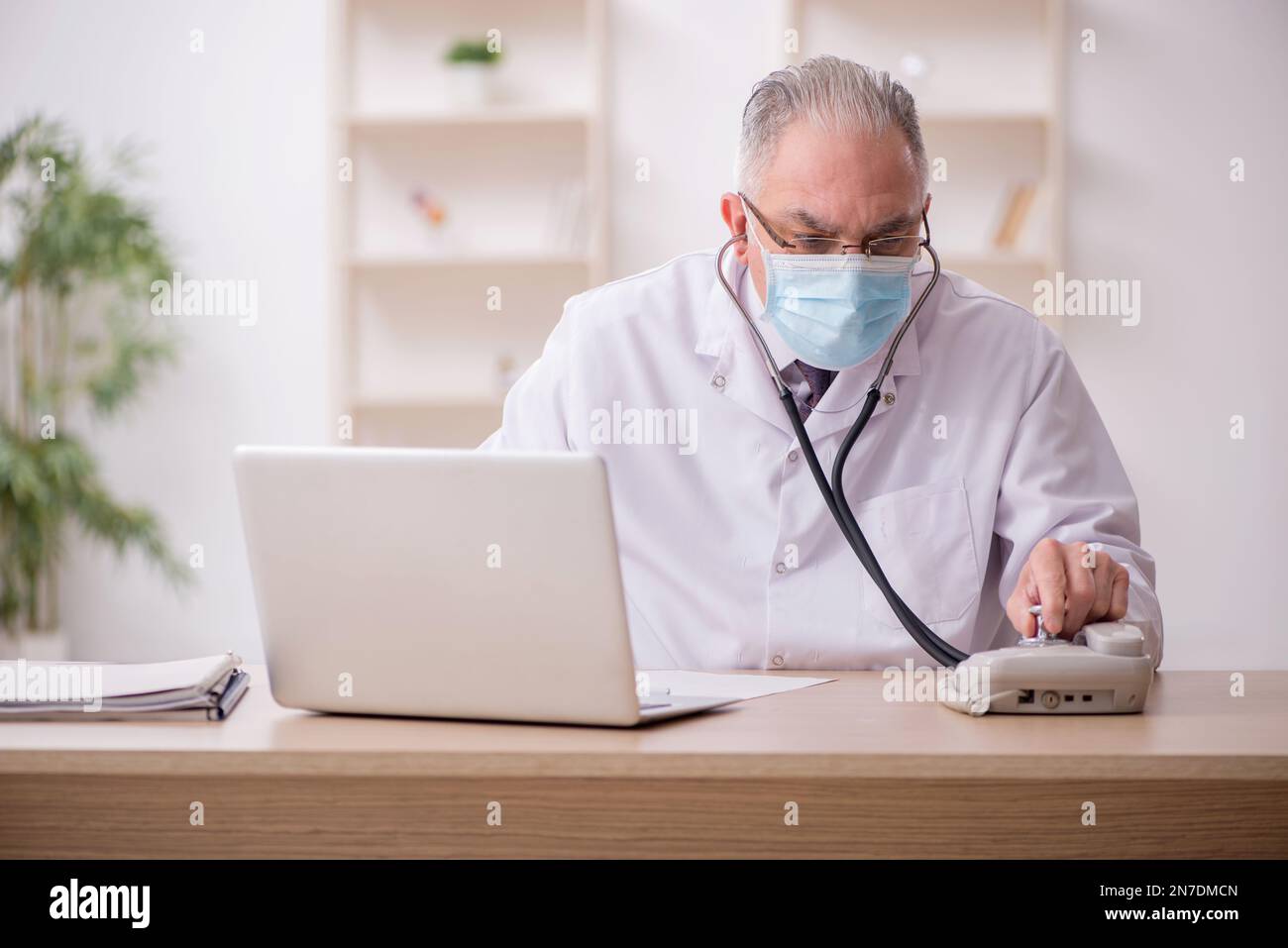 Old doctor working in the clinic during pandemic Stock Photo - Alamy