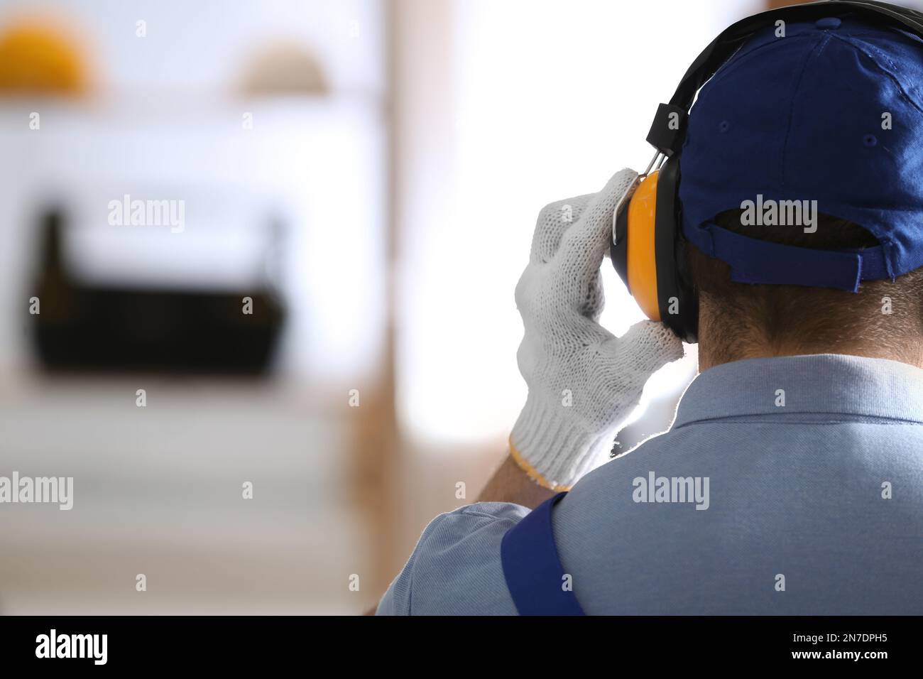 Worker wearing safety headphones indoors, back view with space for text ...