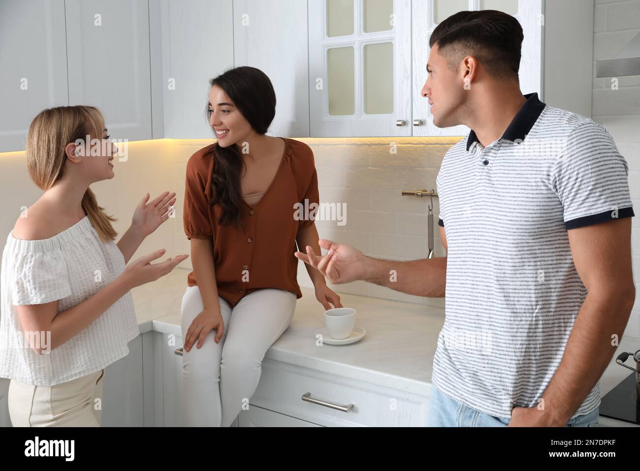Group of people having conversation in kitchen Stock Photo - Alamy