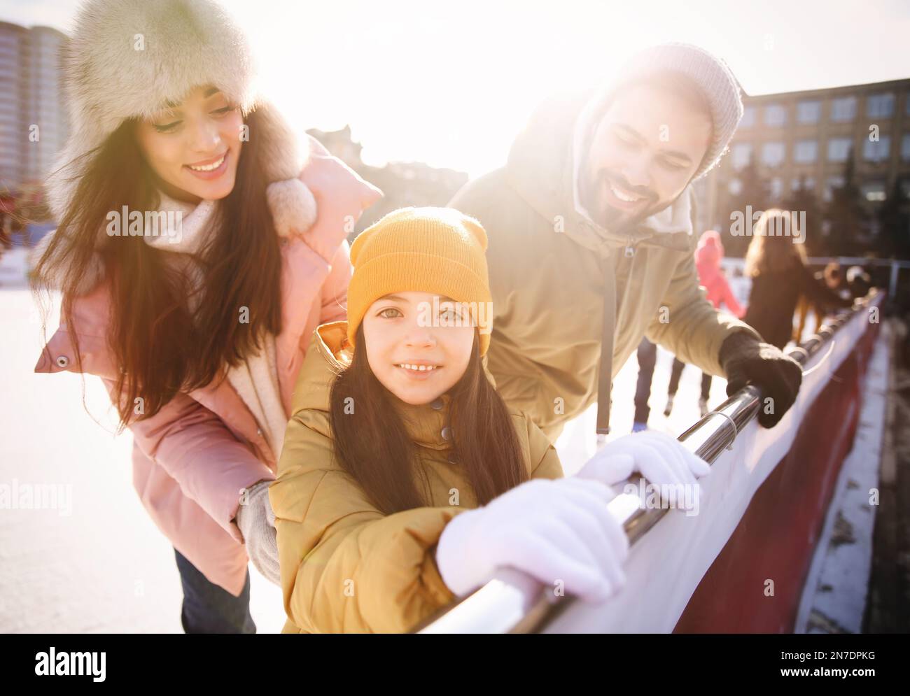 Cute little girl with her parents at outdoor ice skating rink Stock ...