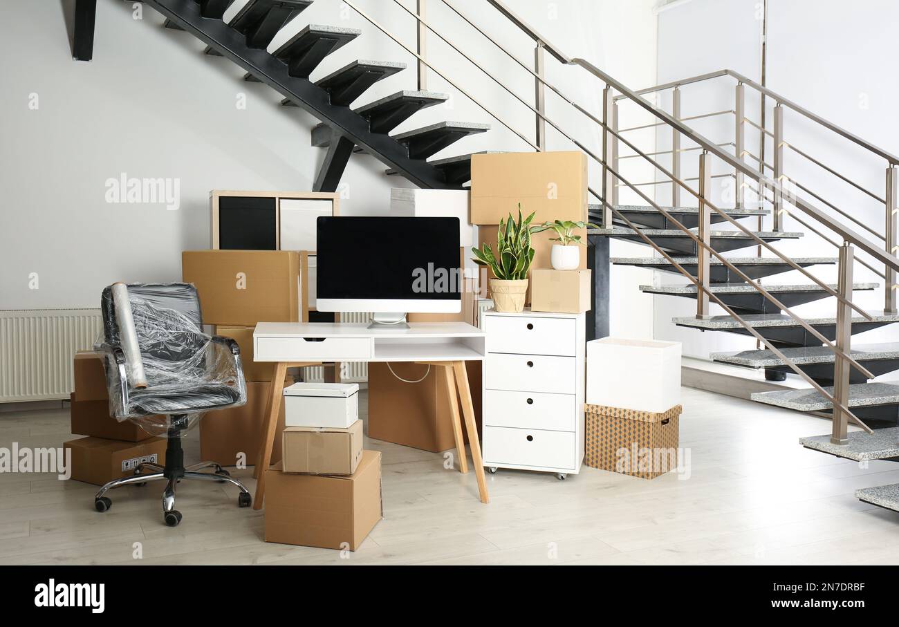 Cardboard boxes and furniture near stairs in office. Moving day Stock ...