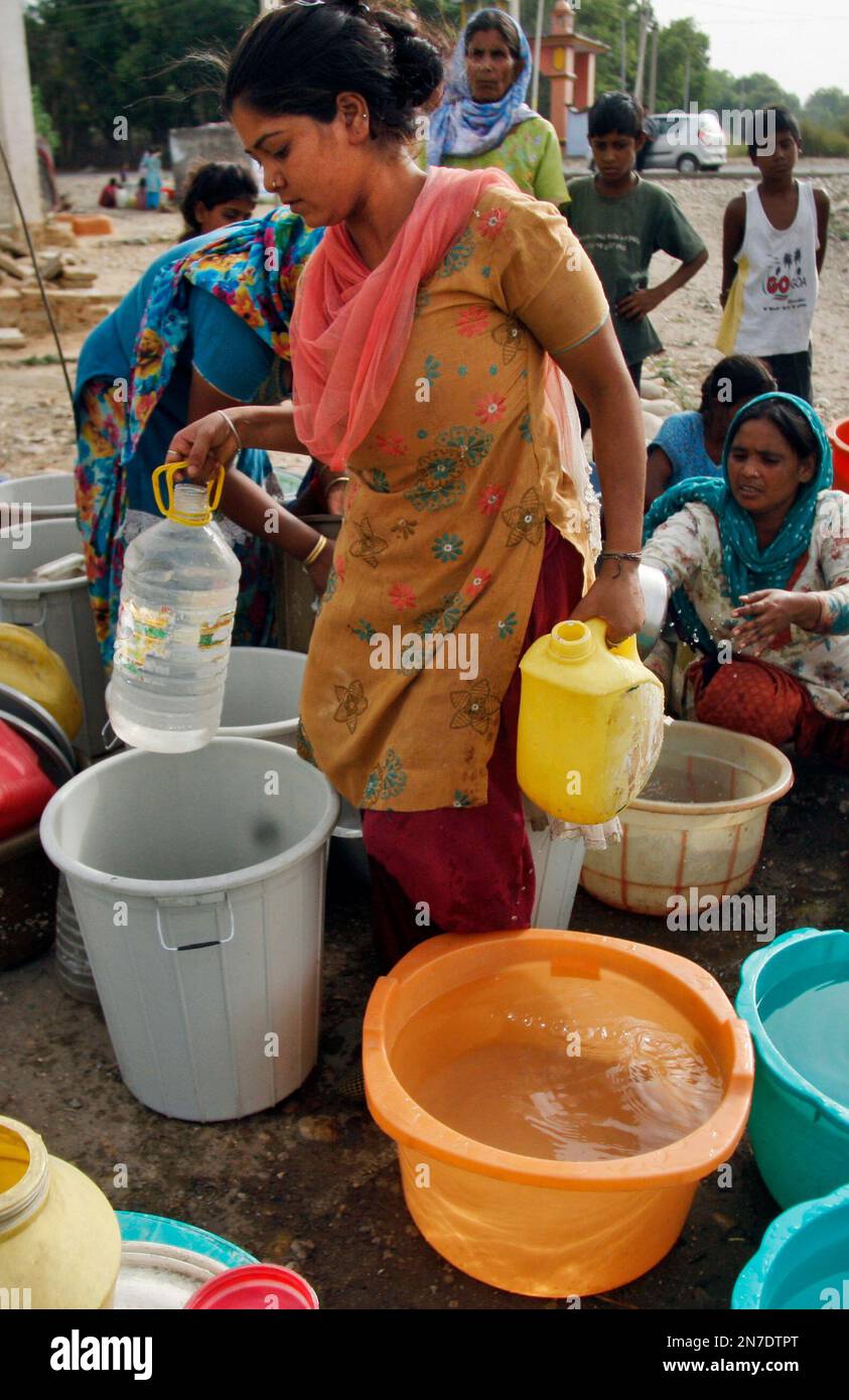 In this Sunday, May 26, 2013 photo, an Indian woman carries containers ...