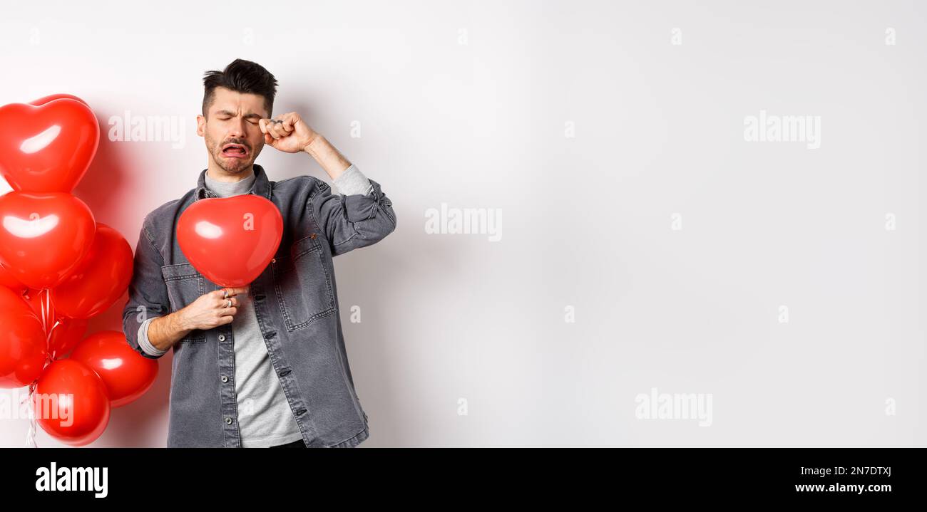 Valentines day and love concept. Sad crying man holding red heart ...
