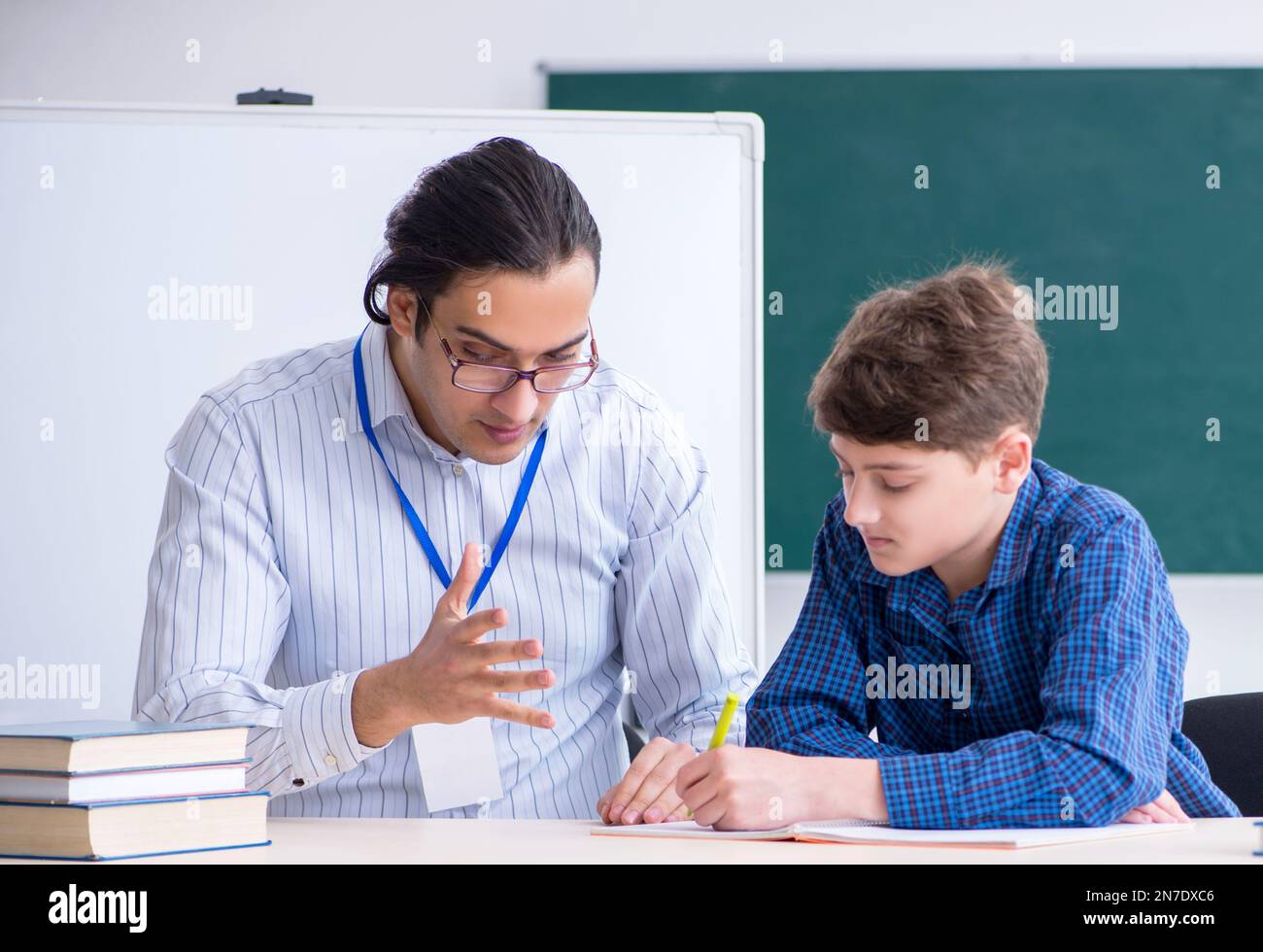 The young male teacher and boy in the classroom Stock Photo - Alamy