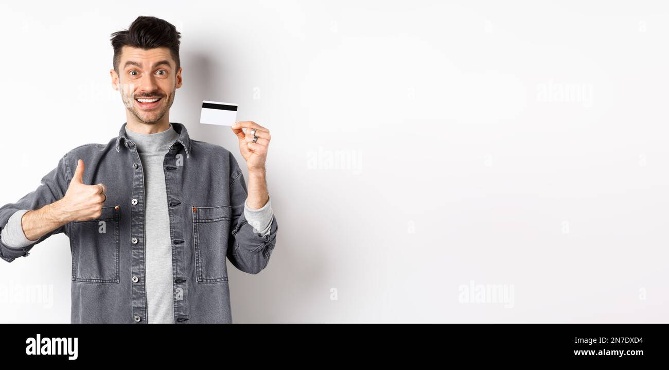 Very good. Smiling guy with plastic credit card showing thumbs up ...