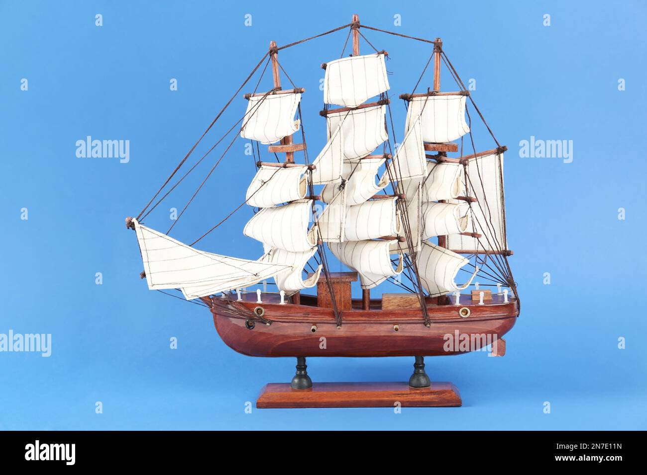 Miniature model of old ship with white sails on blue background Stock ...