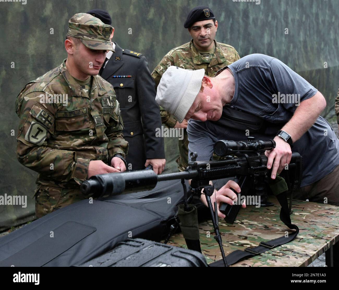 Georgian soldiers show a sniper's submachine gun to a visitor, right ...