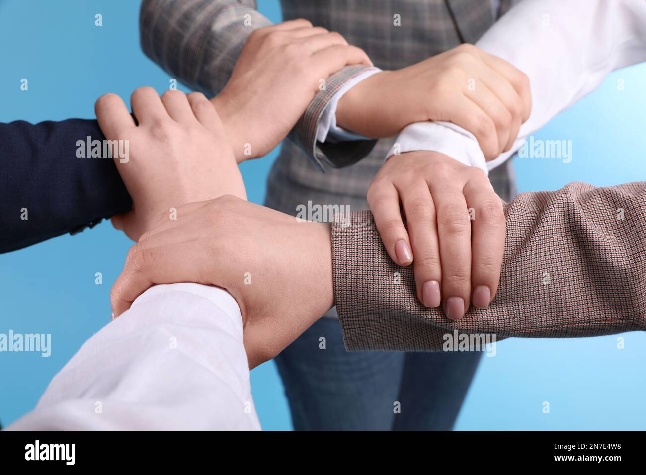 Women joining hands together on light blue background, closeup Stock ...