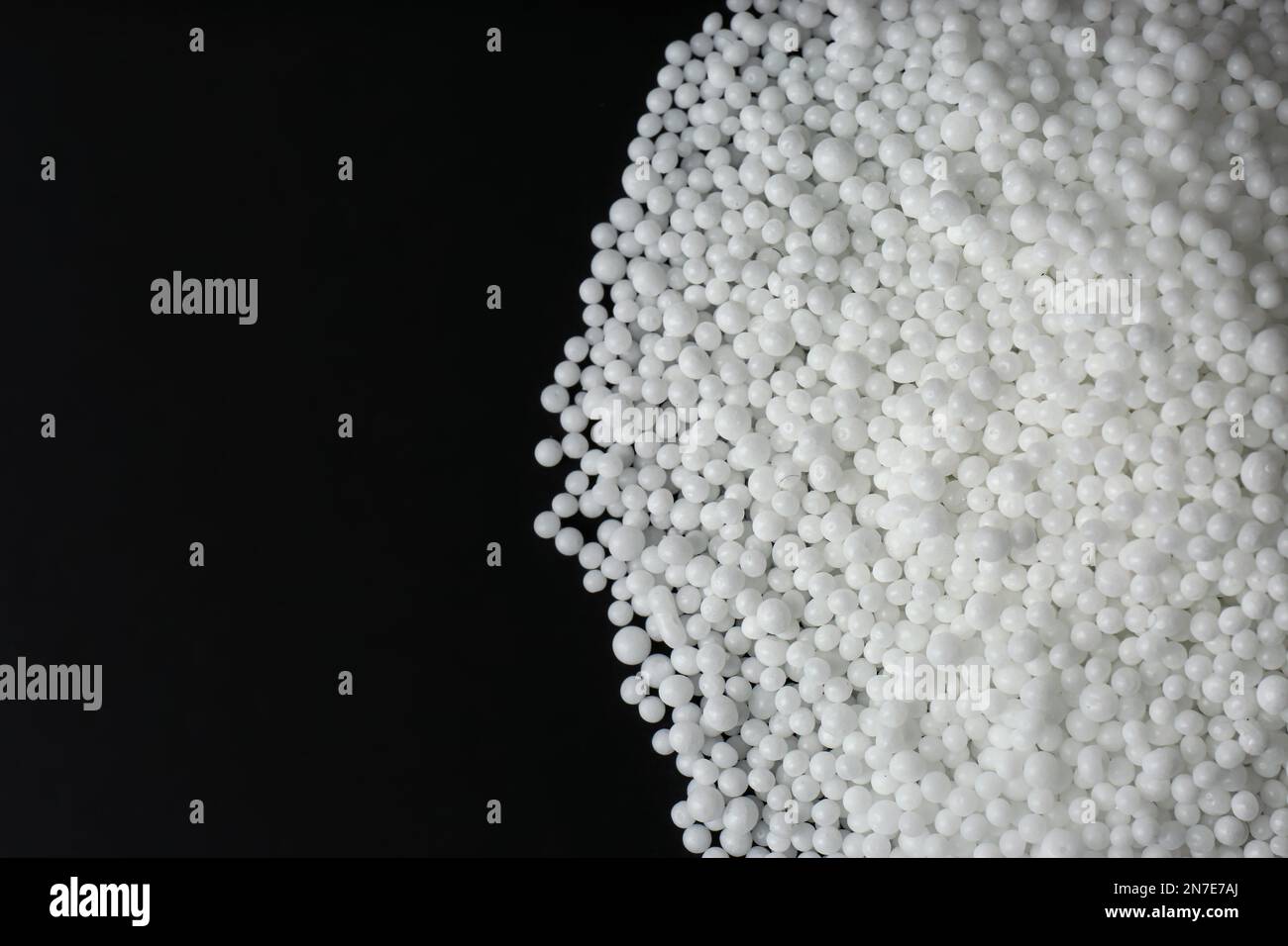 Pellets of ammonium nitrate on black background, flat lay with space ...