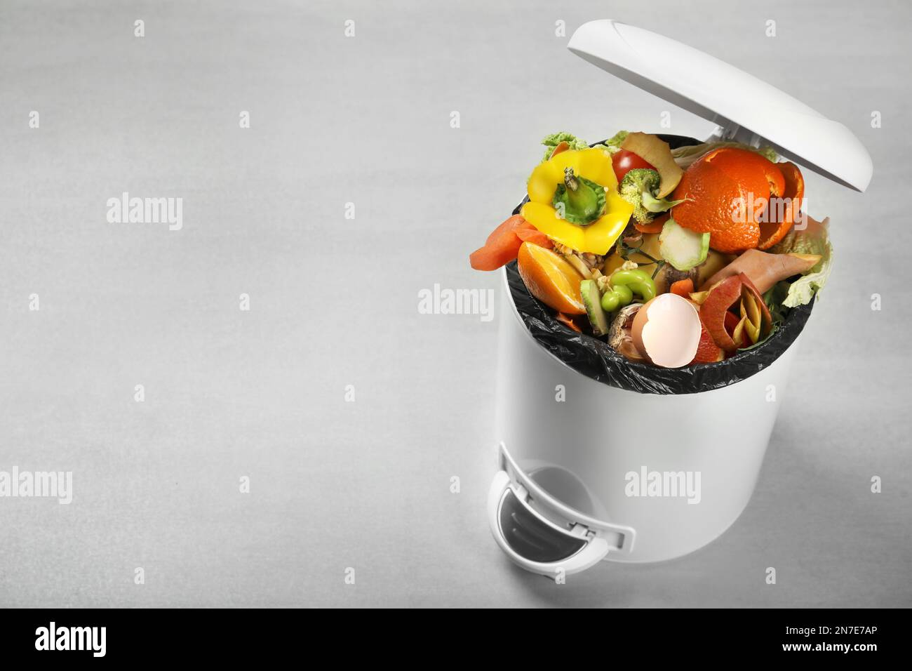 Trash bin with natural garbage on light background, space for text ...