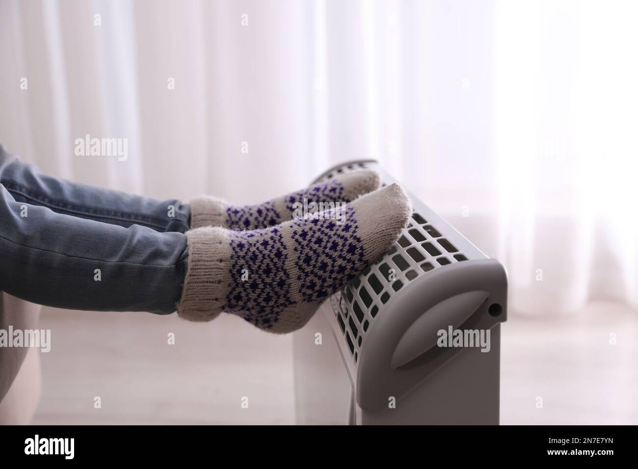 Child warming feet on electric heater at home, closeup Stock Photo - Alamy