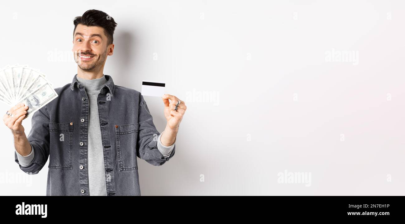 Happy guy showing plastic credit card and dollar bills, giving choice ...