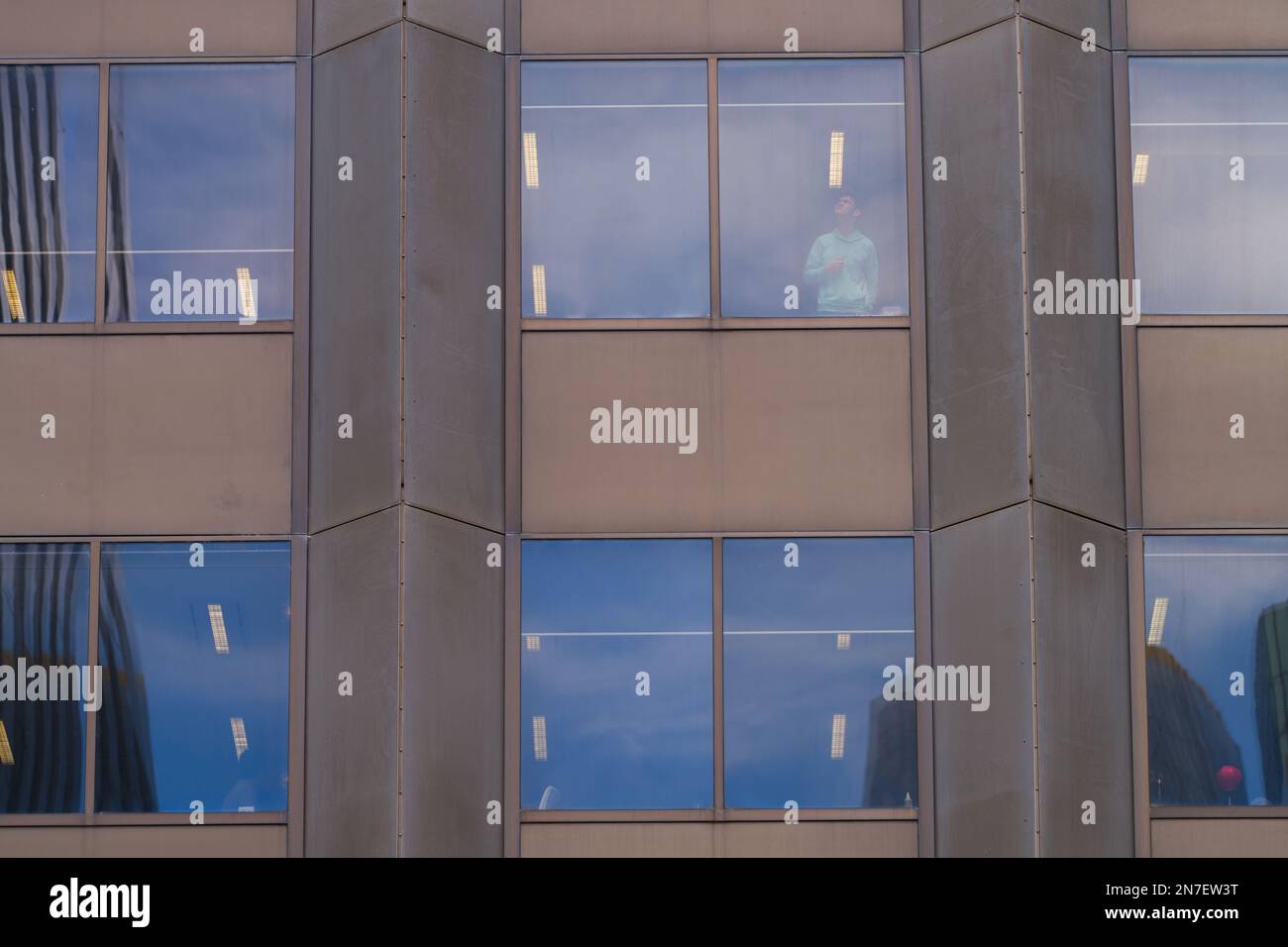 Person in office window looking up in day time showing glass windows ...