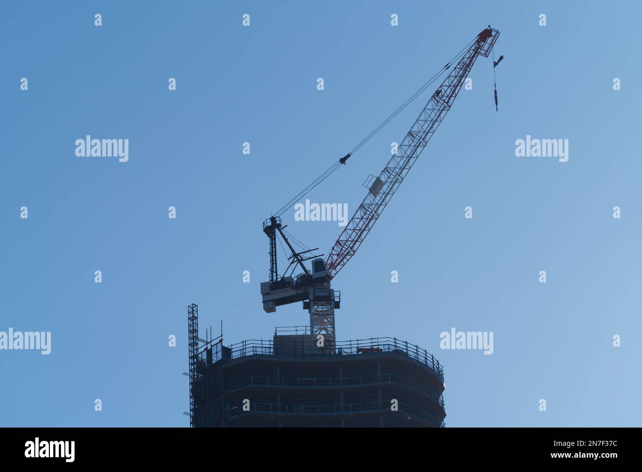 Skyscraper construction crane on a building site with a blue sky ...