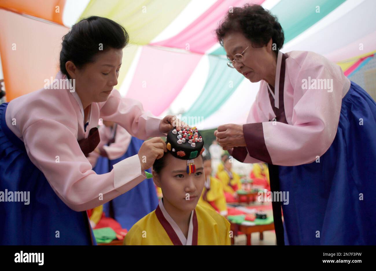 Two women make an adjustment to a girl's hair at the 41st Coming of Age ...