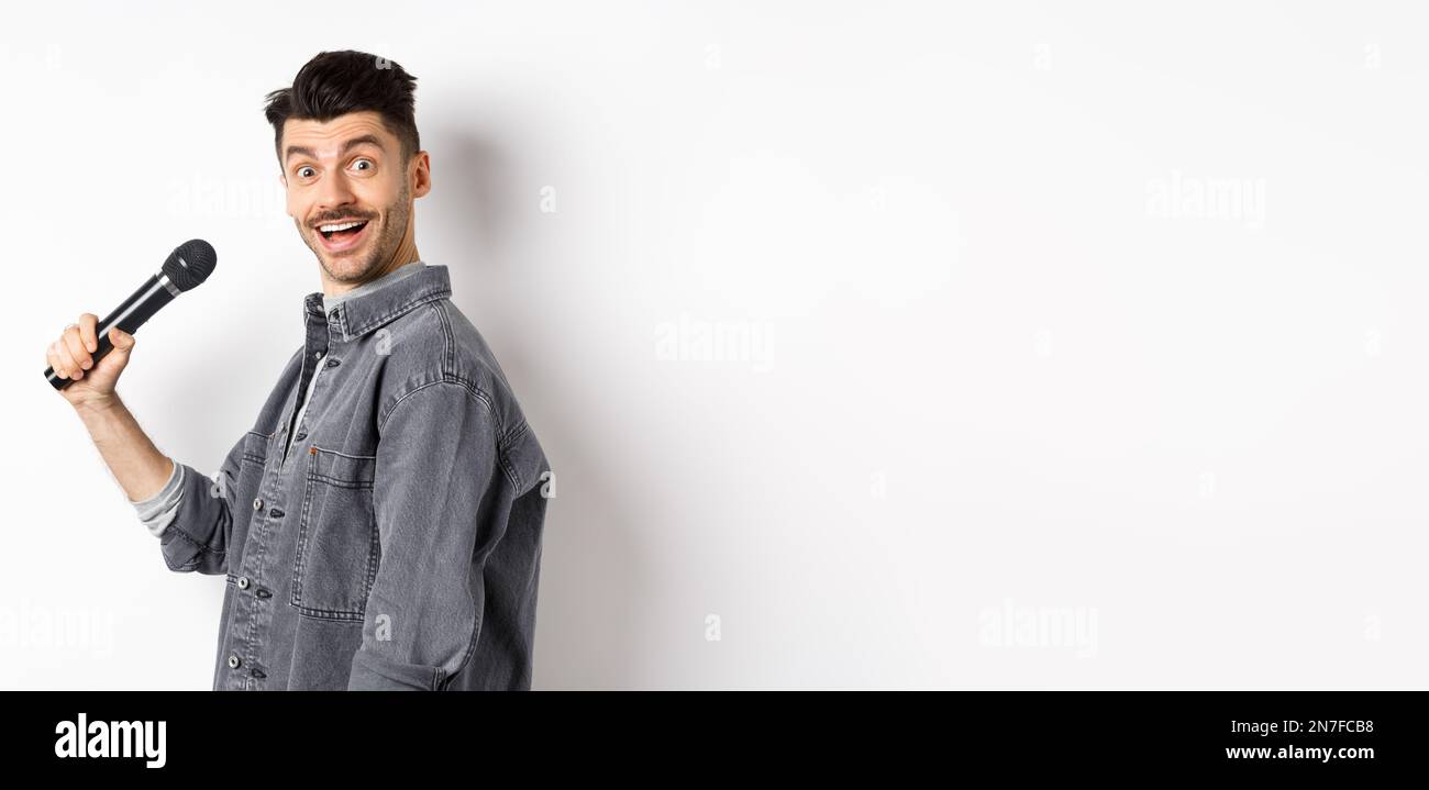 Profile of handsome smiling man holding mic, turn head at camera with ...