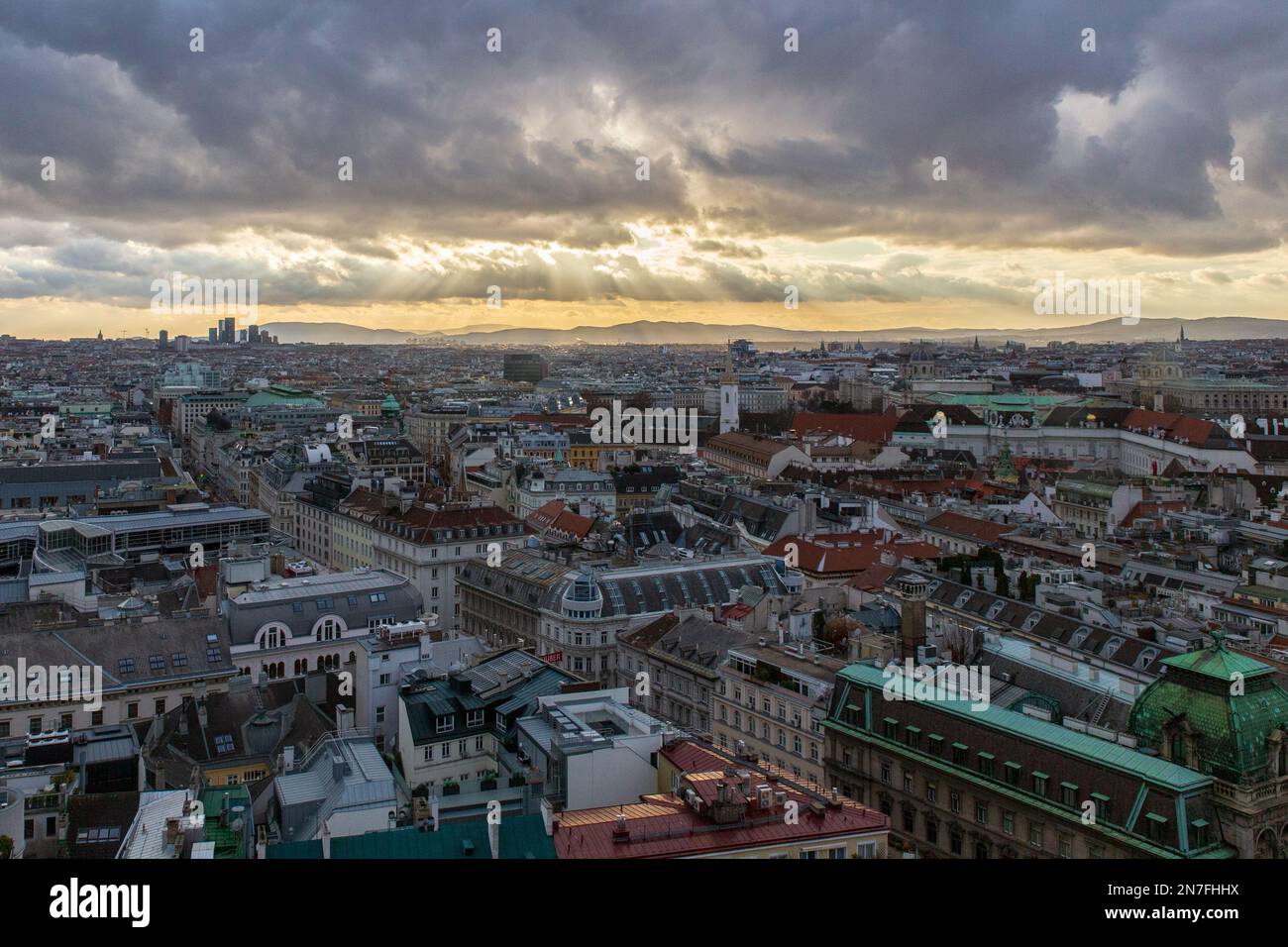 An aerial of the rooftops of Vienna during sunset with floating clouds ...