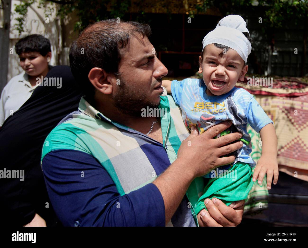 Ali Arar holds his one-year-old wounded son, Aqeel Ali, at the scene of ...