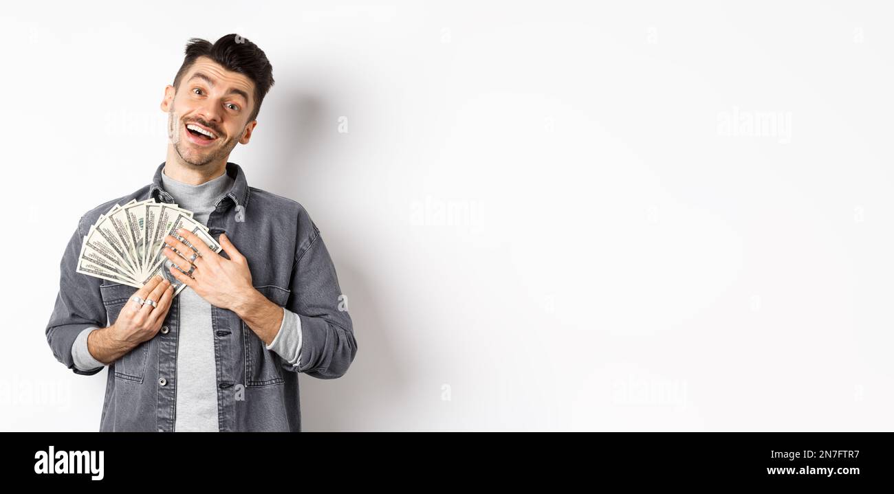 Happy smiling guy making money, hugging dollar bills with pleased ...