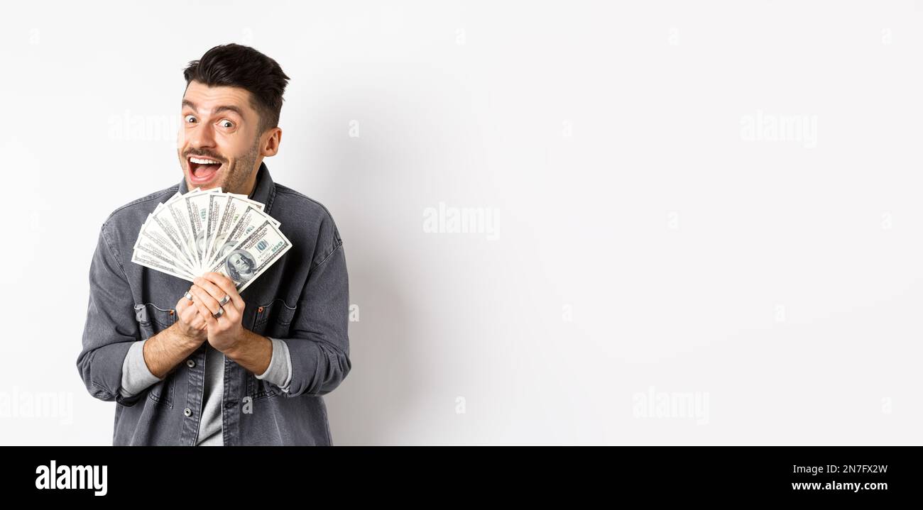 Excited young man smiling and showing dollar bills, making money ...