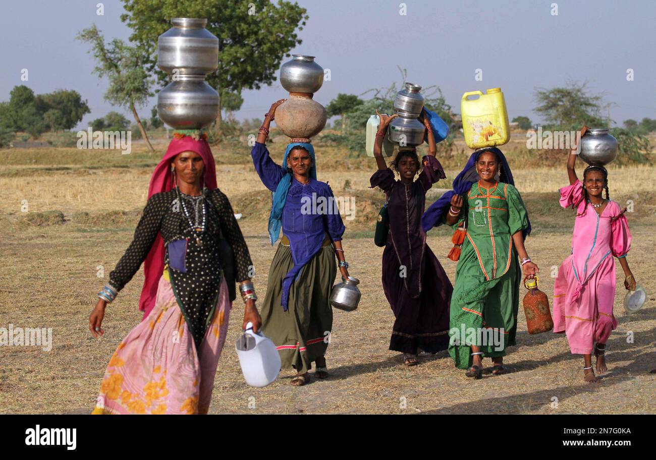 Indian girls and women carry water in pitchers on their heads near ...
