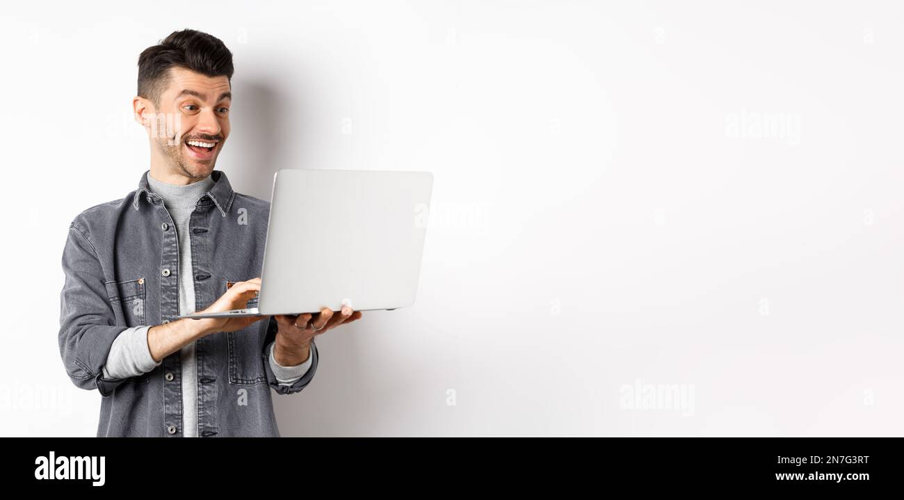 Man watching funny video on laptop, laughing at computer screen and ...