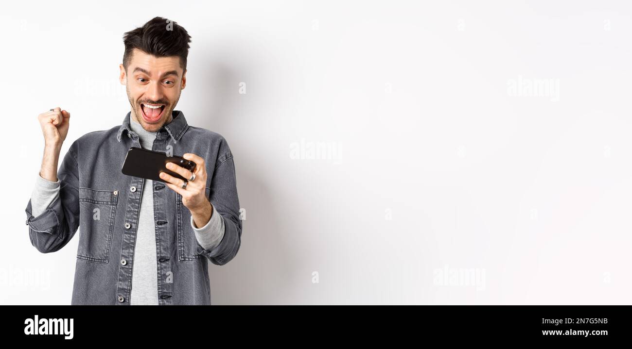 Happy man shouting yes, winning video game on mobile phone and ...