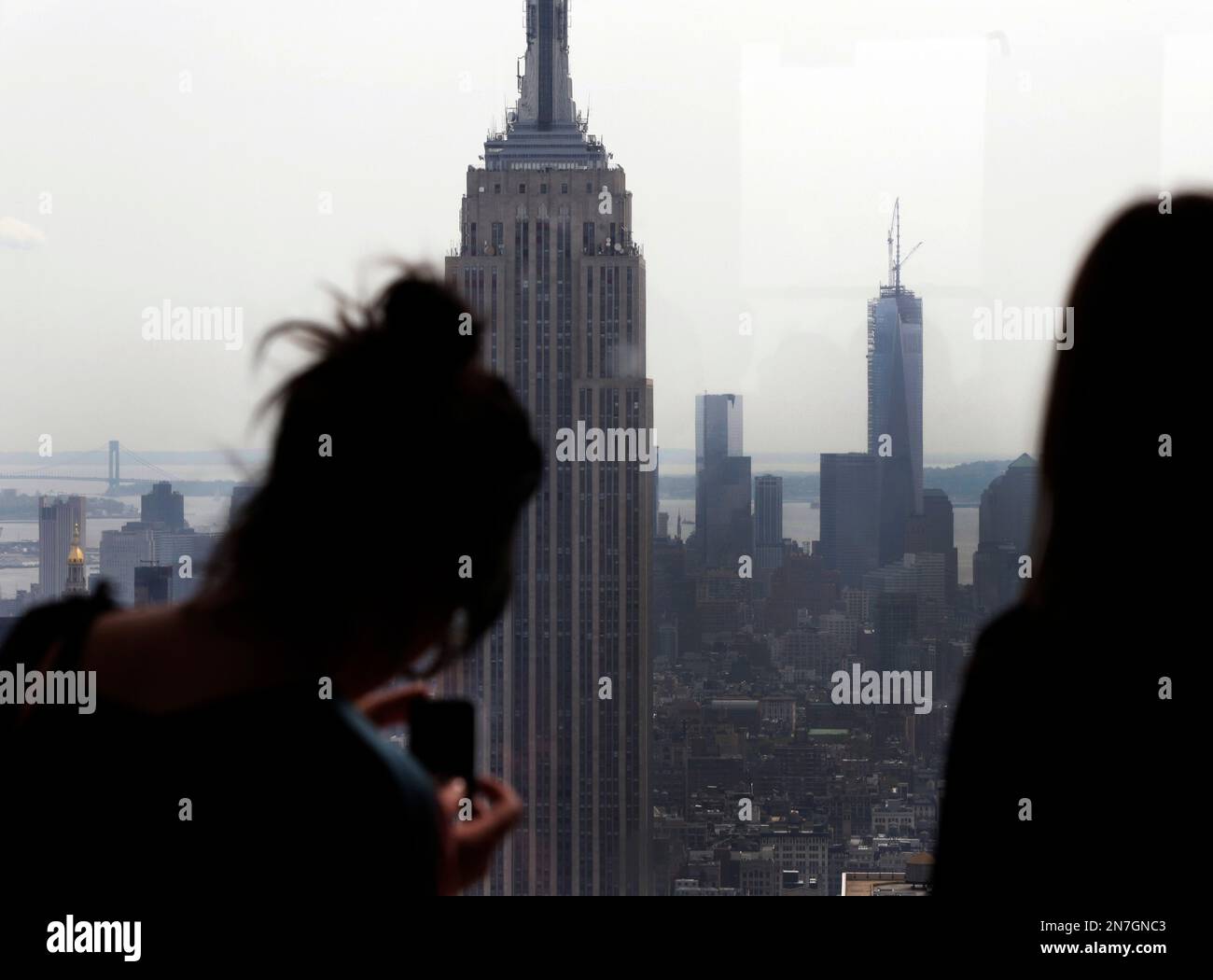 A woman takes a photo of the 1,454-foot Empire State Building, center ...