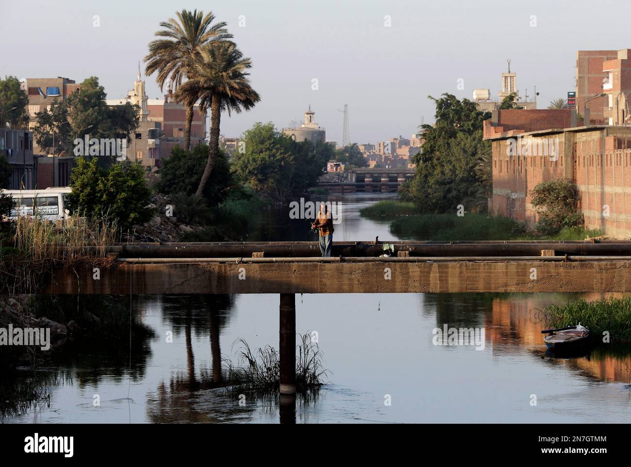An Egyptian man fishes in a water canal, branching out of the Nile ...