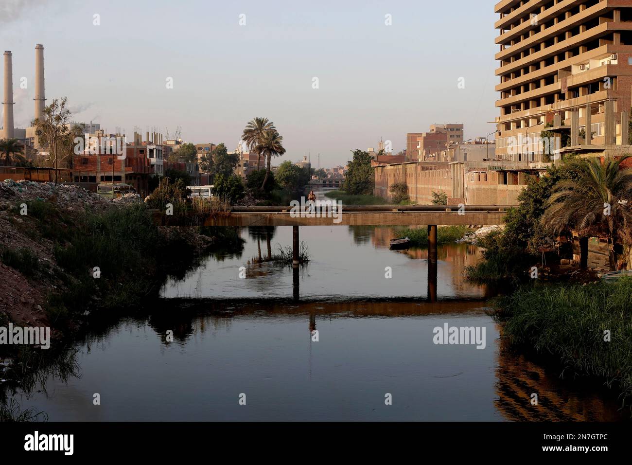 An Egyptian man fishes from a water canal, branching out of the Nile ...