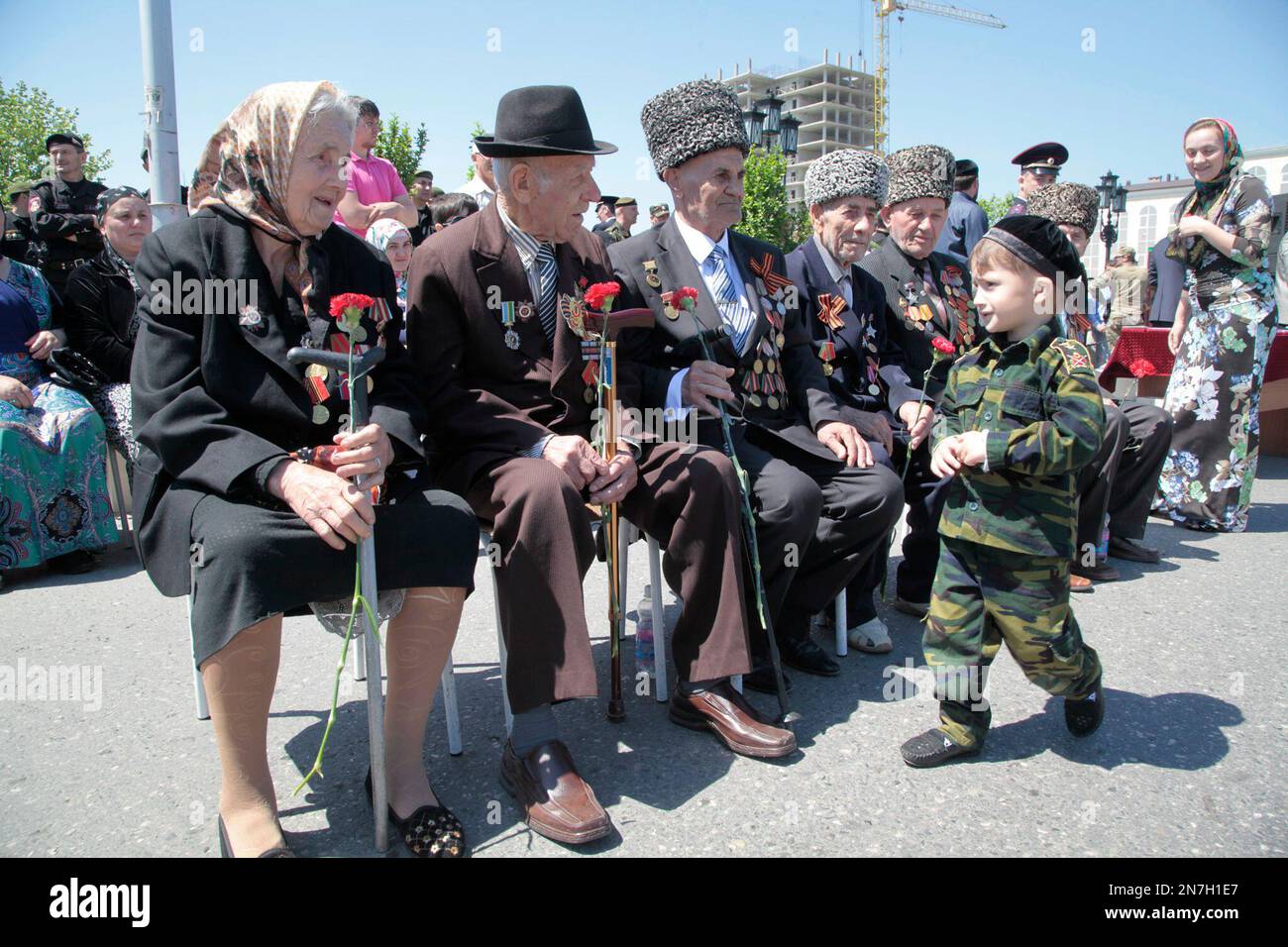 A little Chechen boy passes Chechen WWII veterans during a Victory Day ...