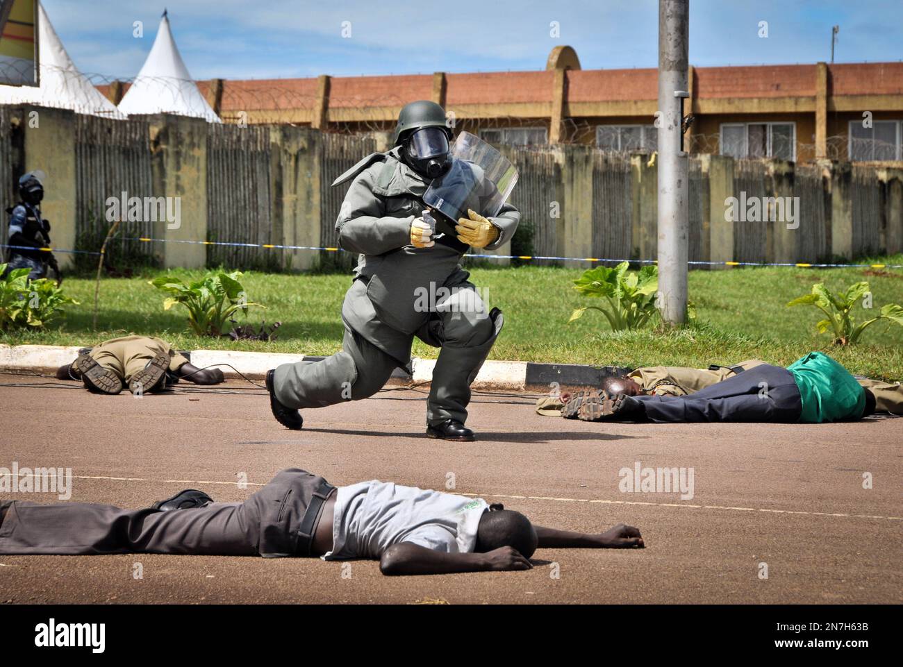 A Ugandan bomb-defusal expert wearing protective equipment carries a ...