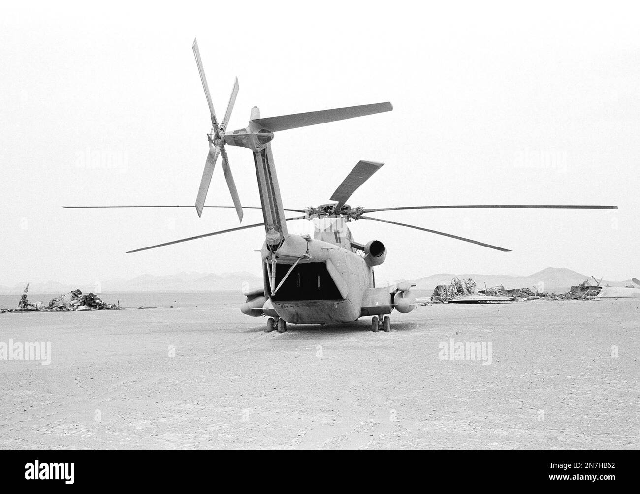 A massive U.S. helicopter stands out against the desert sky as a grim ...