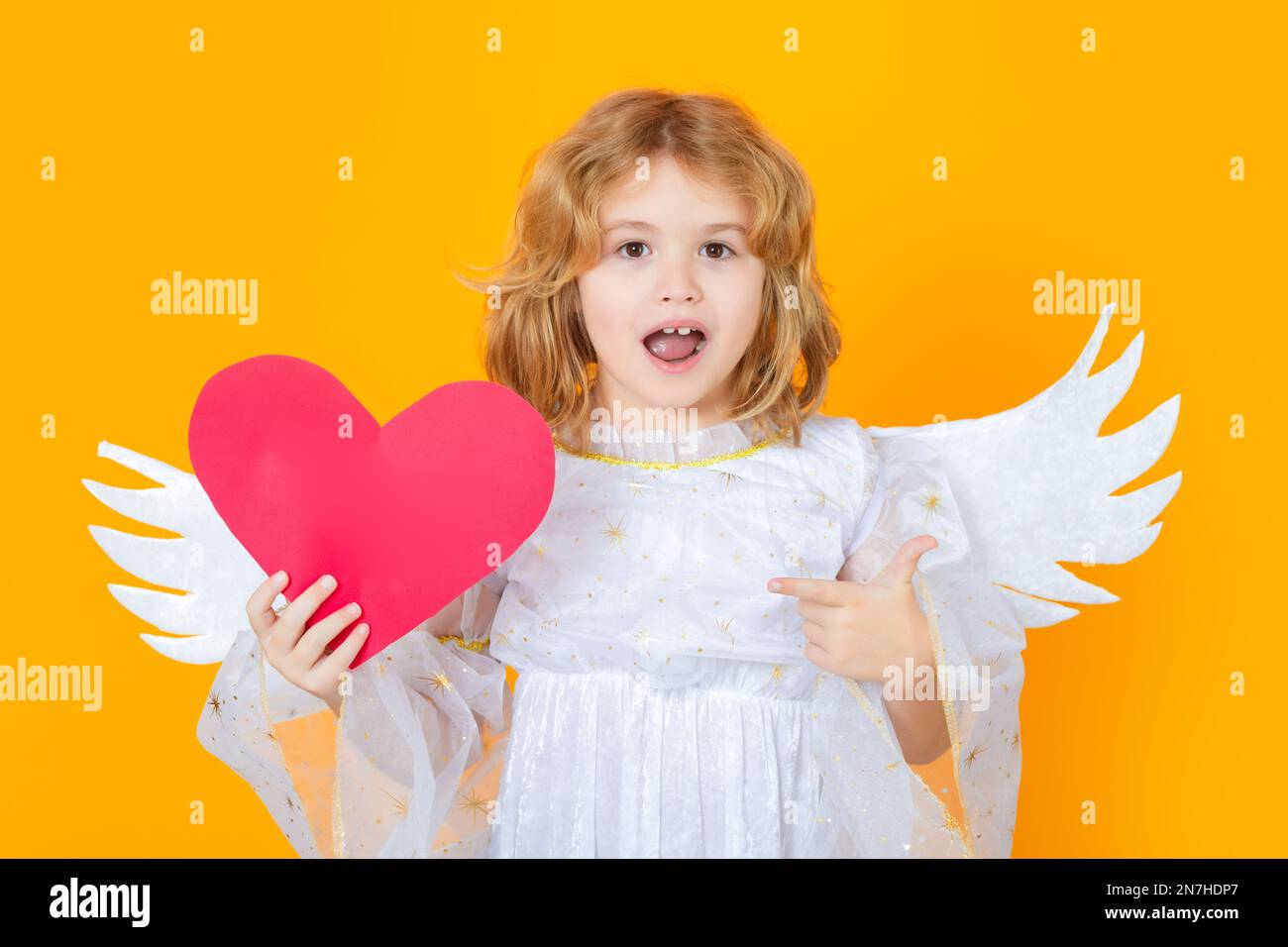 Child angel pointing on paper red heart, point gesture. Kid wearing ...