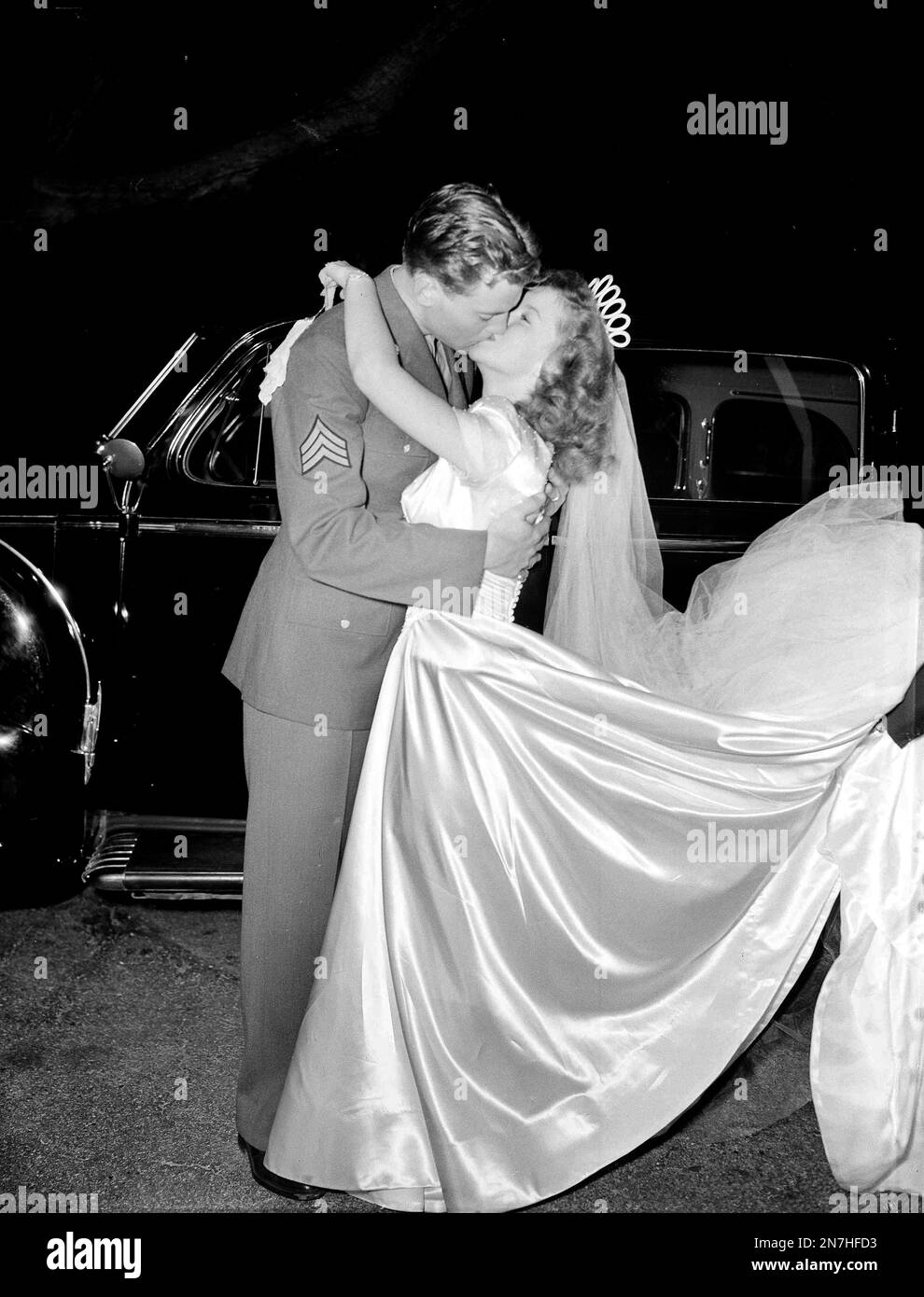 Sgt. John Agar kisses his bride, actress Shirley Temple, as they arrive at the Temple home for a ...