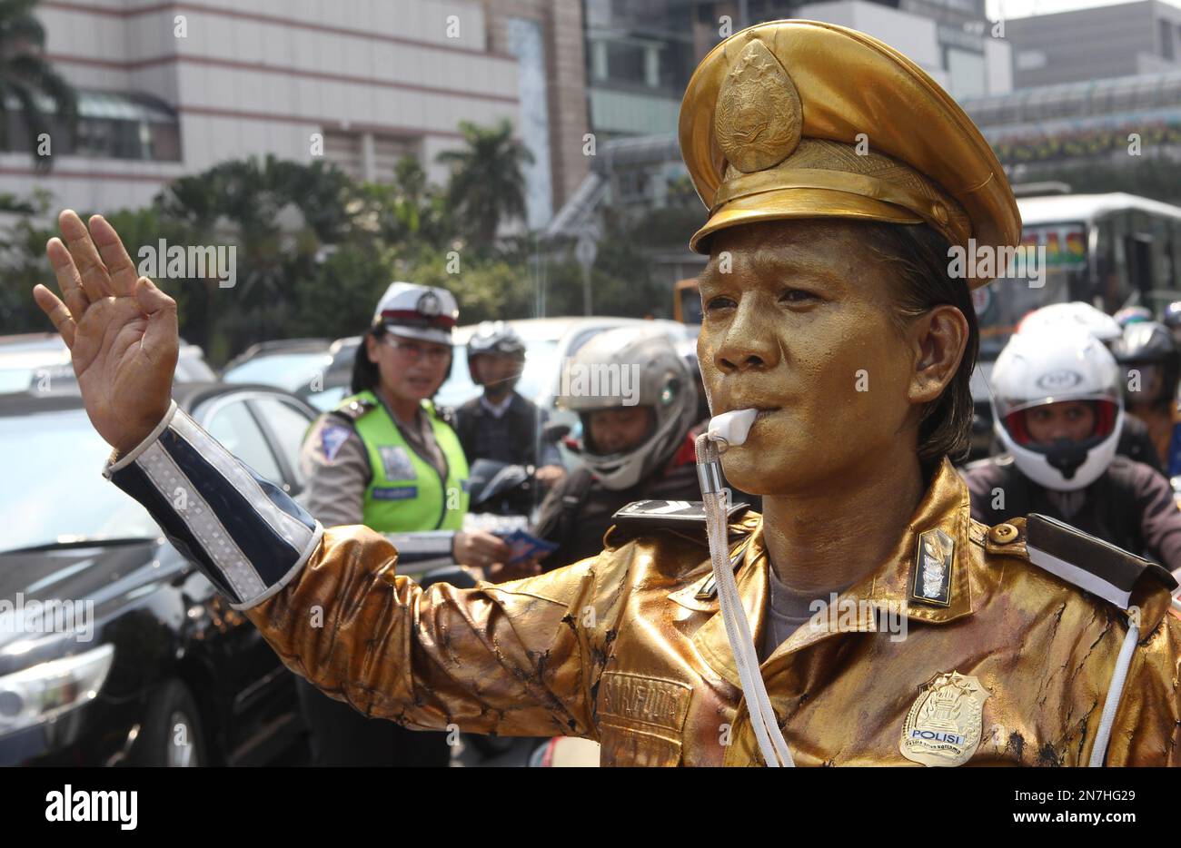 An artist wearing gold-painted traffic police uniform performs on ...