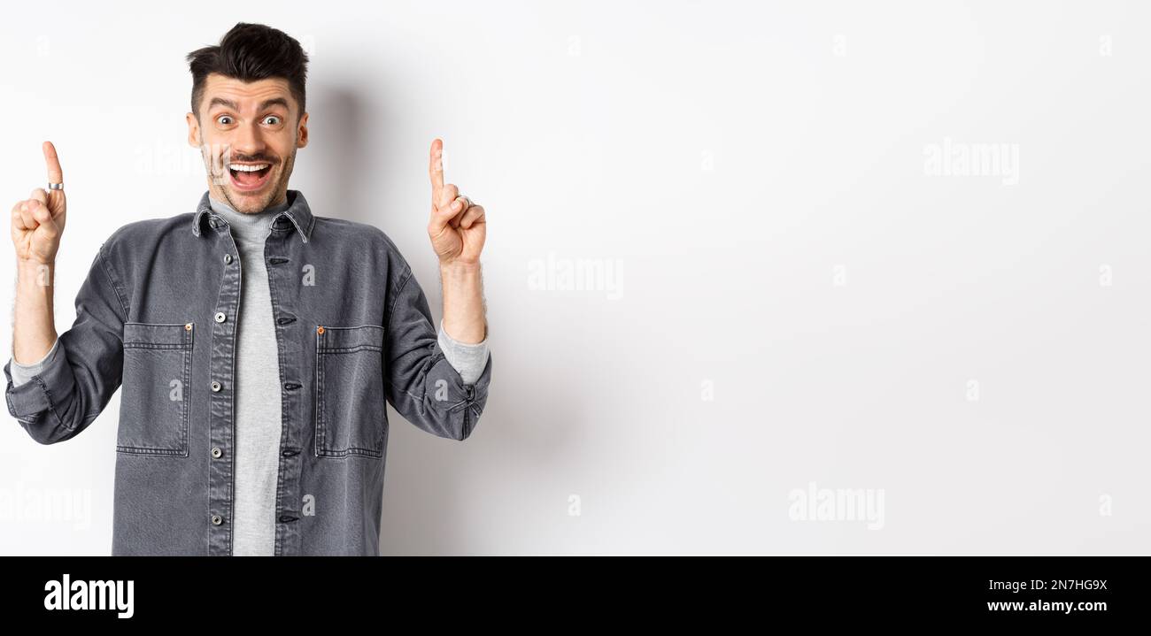 Excited handsome guy pointing fingers up, smiling happy and showing ...