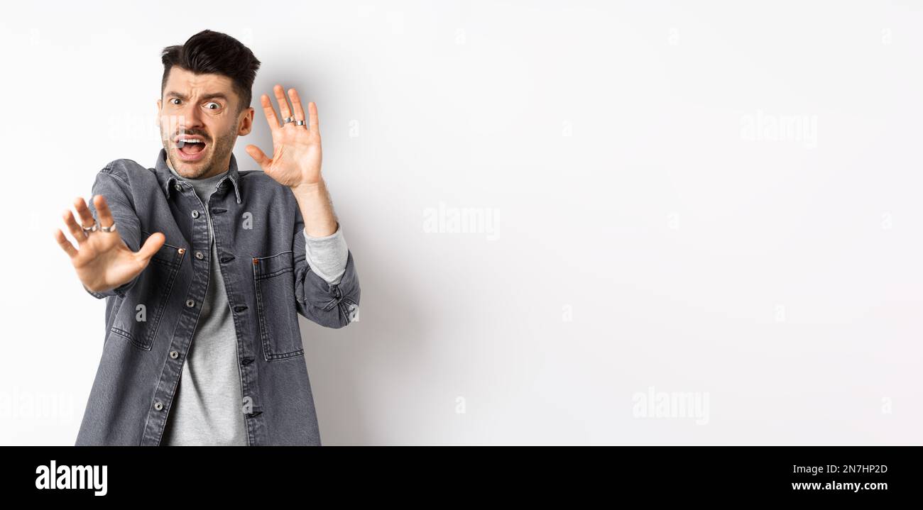 Scared timid guy screaming and raising hands in pleading pose, begging ...