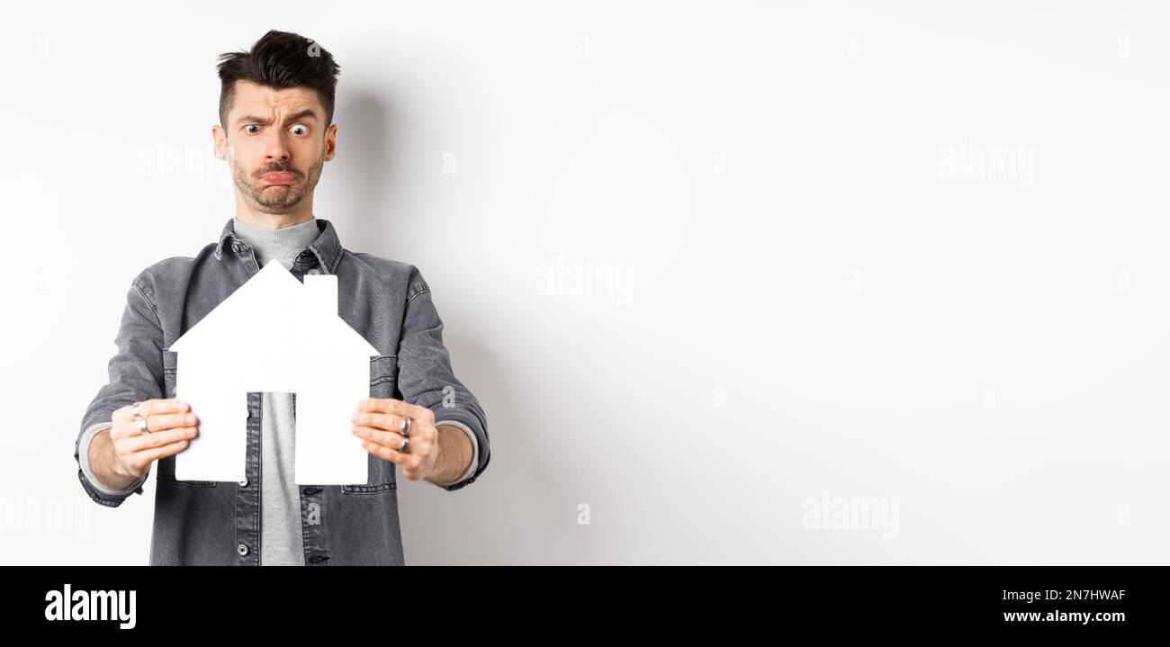 Real estate and insurance concept. Confused guy look at paper house ...