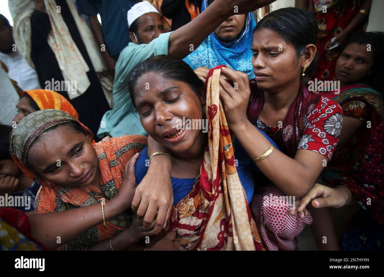 A woman is comforted by family members and others after she identified ...