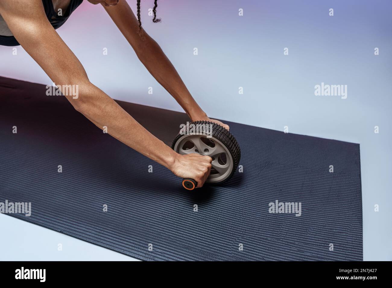 Close up of woman doing exercise with wheel roller on fitness mat on ...