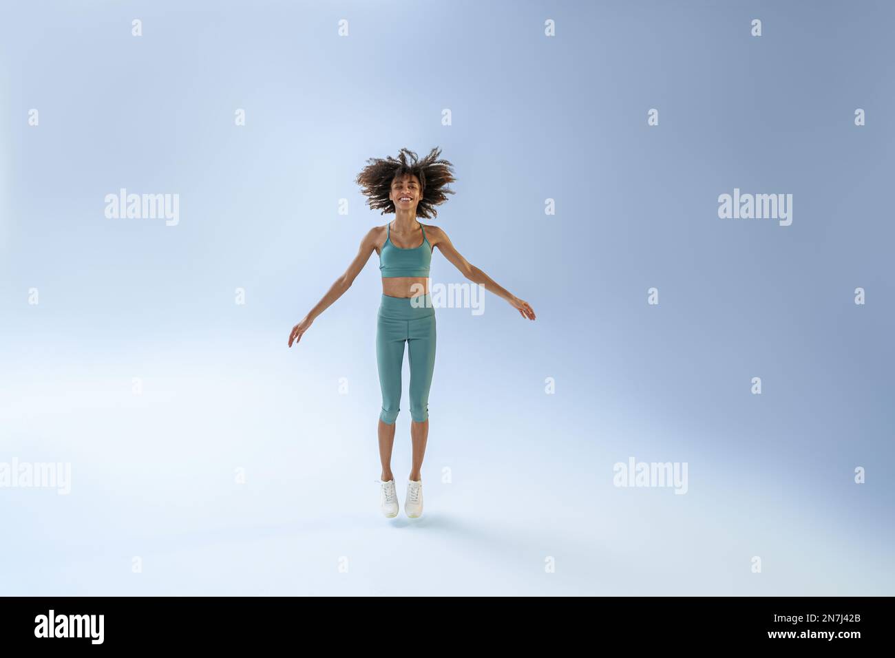 Active sporty woman in sportswear jumping on studio background. Sport ...